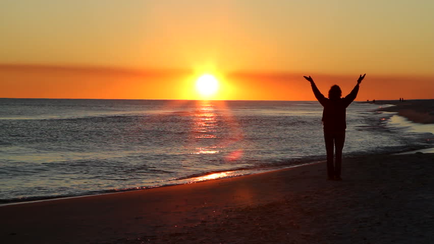 Woman Stands On The Beach Raising Her Hands Into The Arm In Prayer And ...